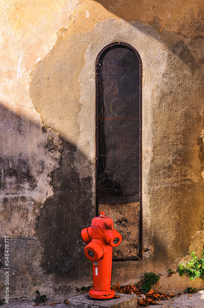 front view, medium distance of a red fire hydrant with concrete wall ...