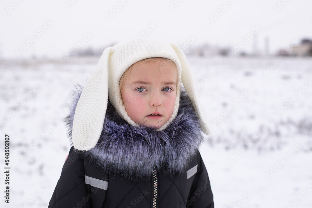 A little girl in winter clothes on the street is crying, tears on her ...