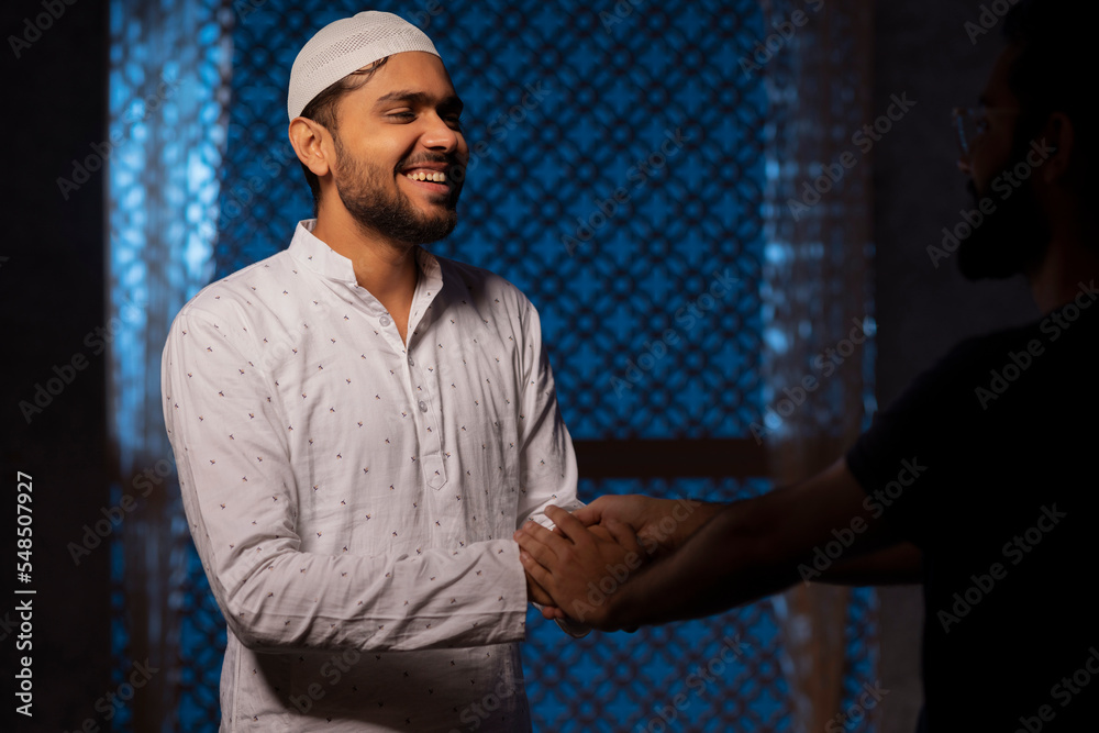 Smiling Muslim man shaking hand with his friend Stock Photo | Adobe Stock