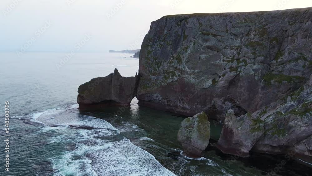 Aerial view of beautiful sea stack and dark cliffs in sunset. Calm ...