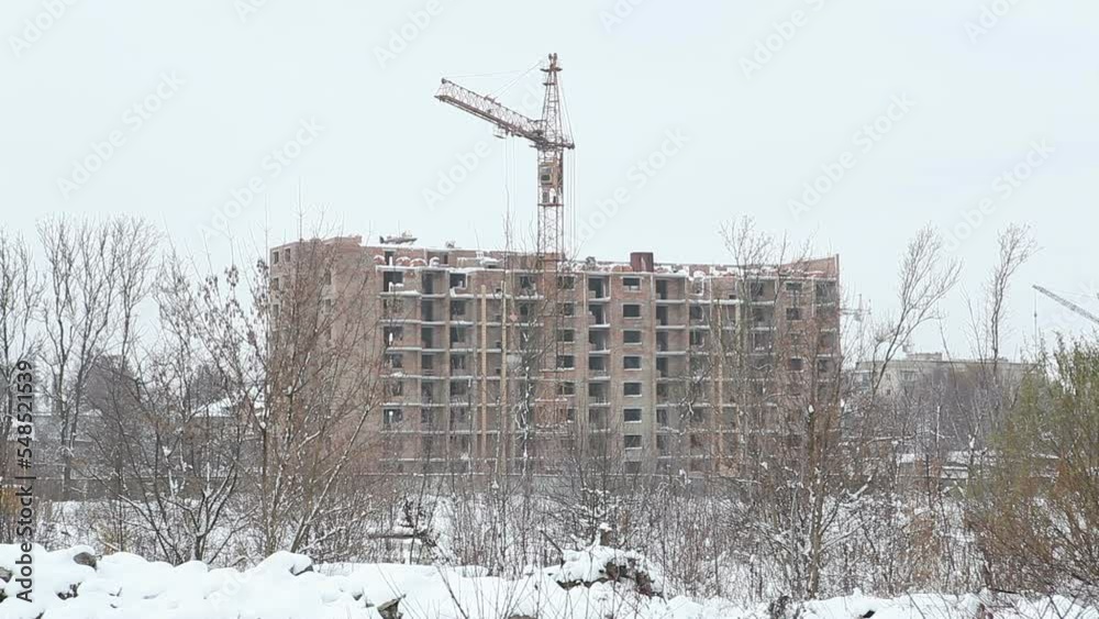 Construction of a multi-storey building in winter. Tower crane works at ...
