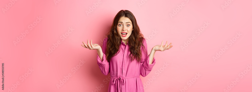 Confused young brunette woman with nervous face expression, raising ...