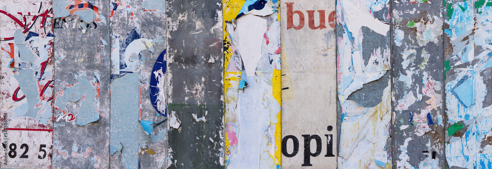 Billboard with remnants of layered advertising signage, torn and peeled ...