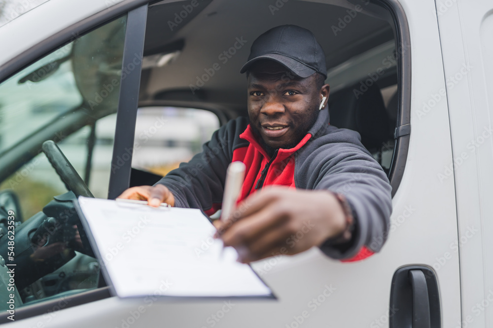 Positive African-American deliveryman behind the wheel of white ...