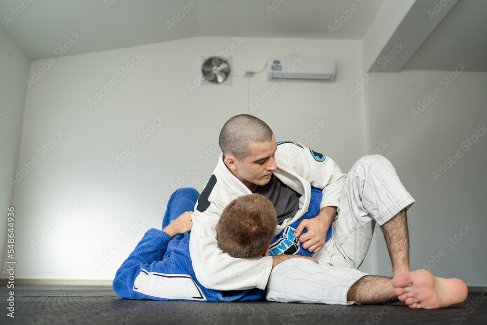 two athletes training Brazilian jiu jitsu kesa gatame side control hold ...