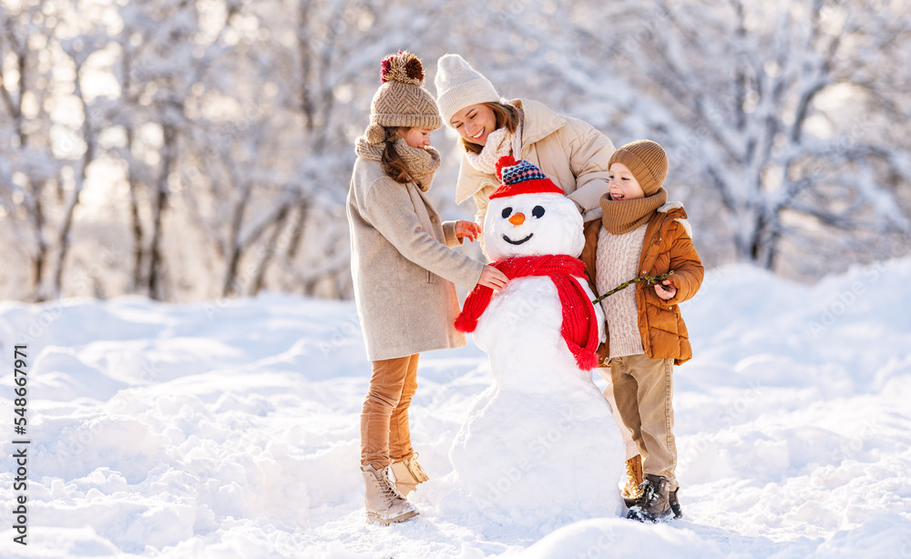 Happy family mother and two little kids making snowman together in ...