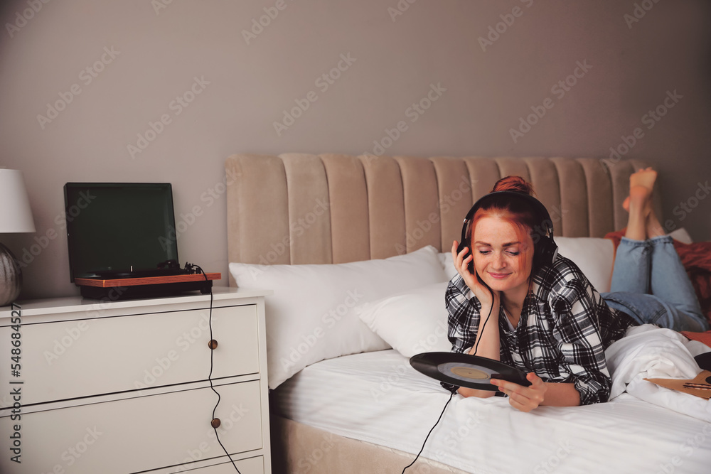 Young woman listening to music with turntable in bedroom Stock Photo ...
