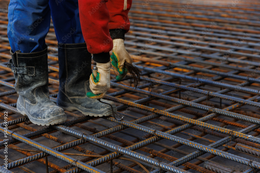 Worker welds reinforcing mesh. Male workers are working on a retaining ...