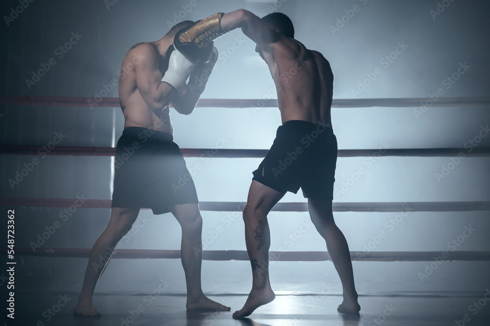 Two shirtless muscular man fighting Kick boxing combat in boxing ring ...