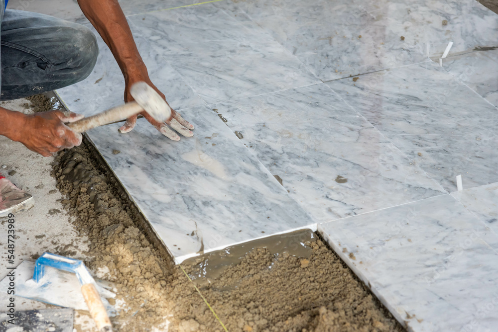 Foto de Tiler installing ceramic tiles on a floor. construction workers ...