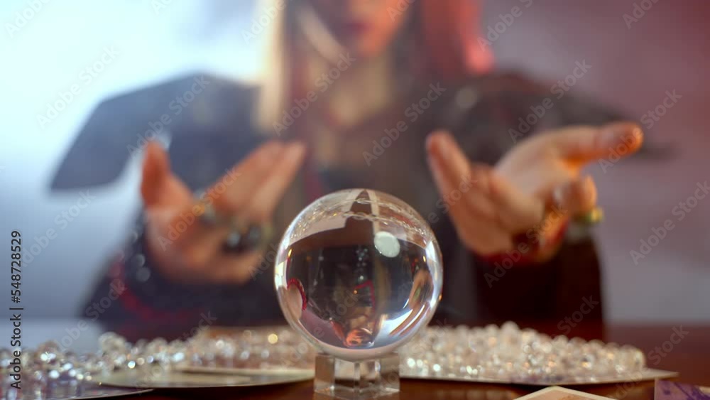 Mystery ritual with round crystal ball in dark illuminated room, gypsy ...