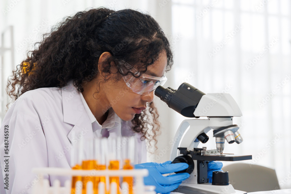 close up, Young woman scientist looking through a microscope in a ...