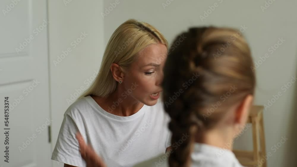 View from shoulder unrecognizable preteen girl to angry young mother scolding, raising voice ...