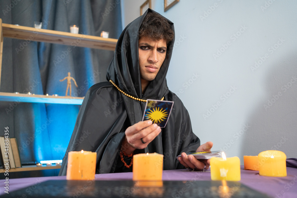 professional fortune teller holding a tarot card in front of the laptop ...