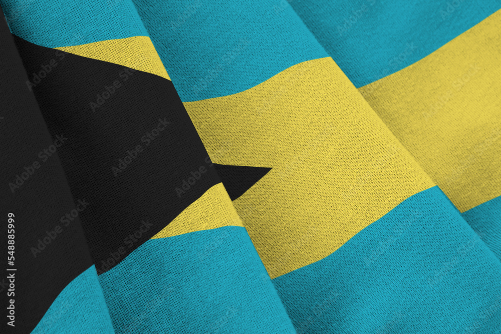 Bahamas flag with big folds waving close up under the studio light ...