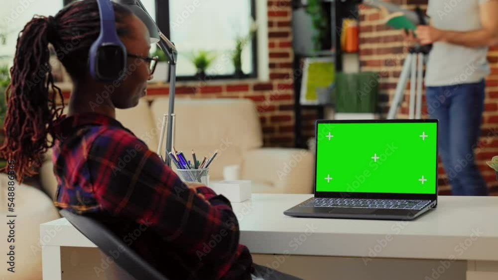 Female freelancer using headphones and working with greenscreen on ...