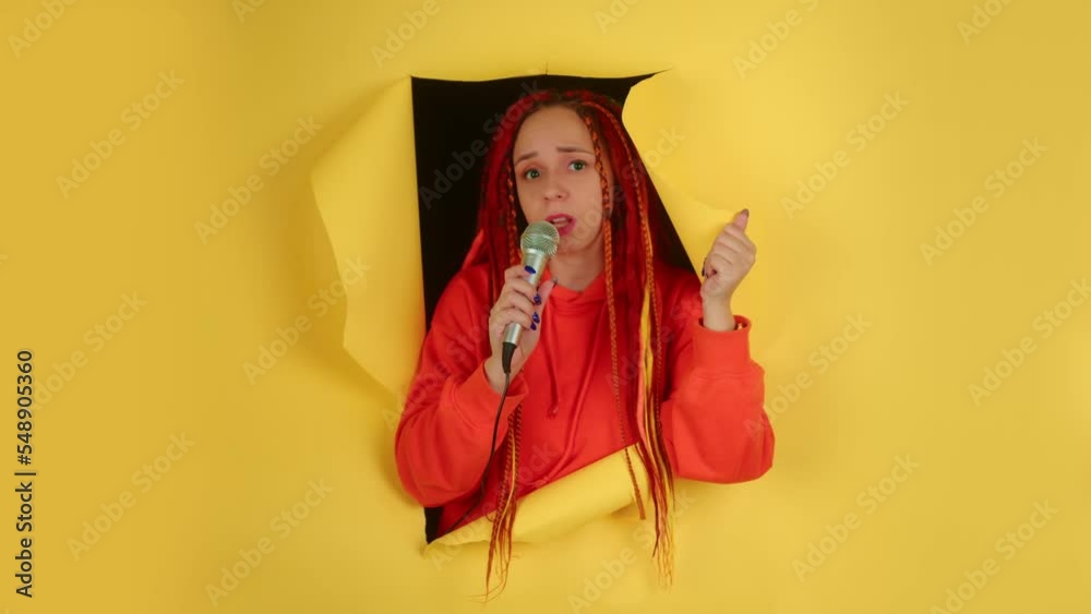 Young woman with bright dreadlocks singing into microphone, sticking ...