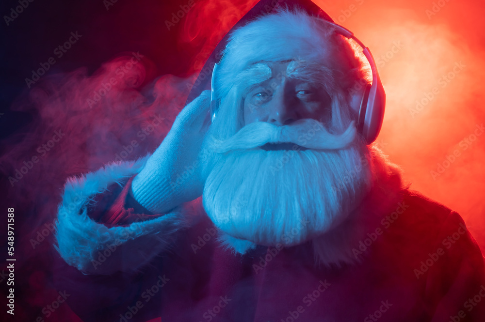 Santa claus listens to music with headphones at a party. Blue red neon ...