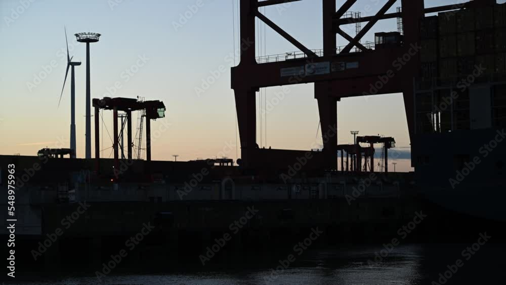 Crane loads container on cargo vessel, nighttime, silhouette, tracking ...