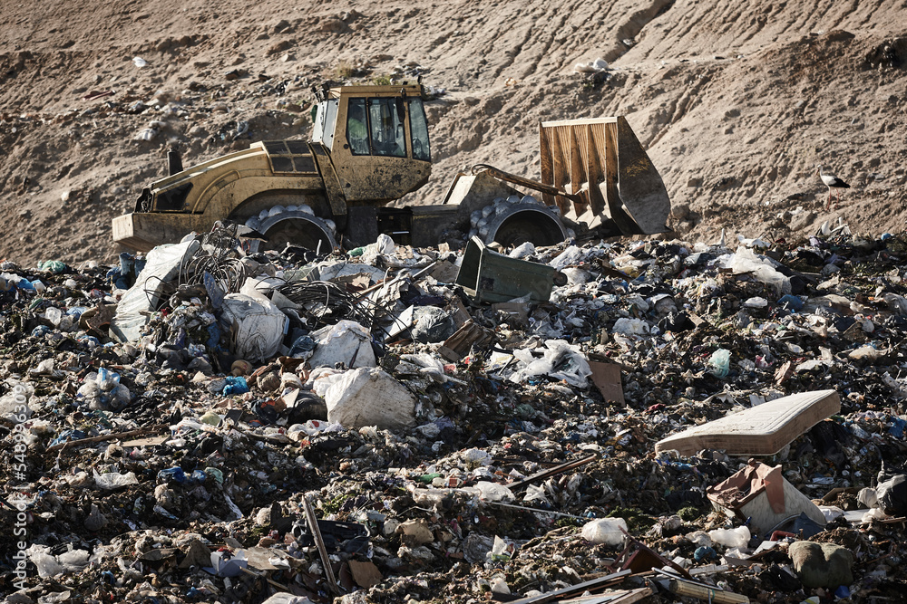 Heavy machinery shredding garbage in an open air landfill. Pollution ...