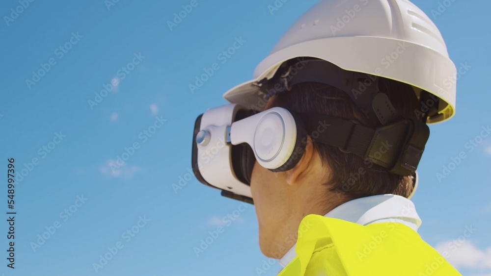 Professional builder in VR helmet standing in front of construction ...