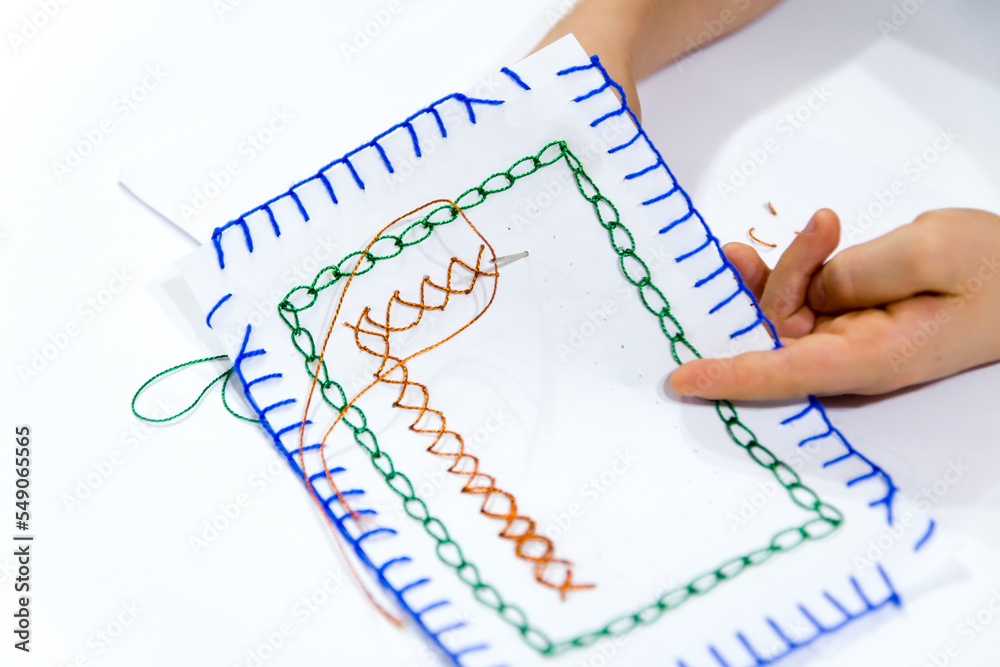 The closeup of hands sewing a colorful card during school activities ...