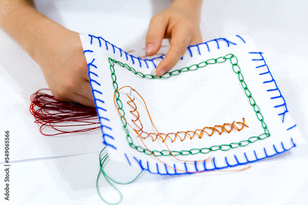 The closeup of hands sewing a colorful card during school activities ...