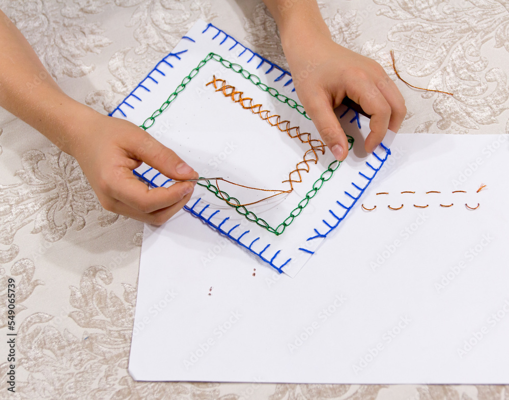 The closeup of hands sewing a colorful card during school activities ...