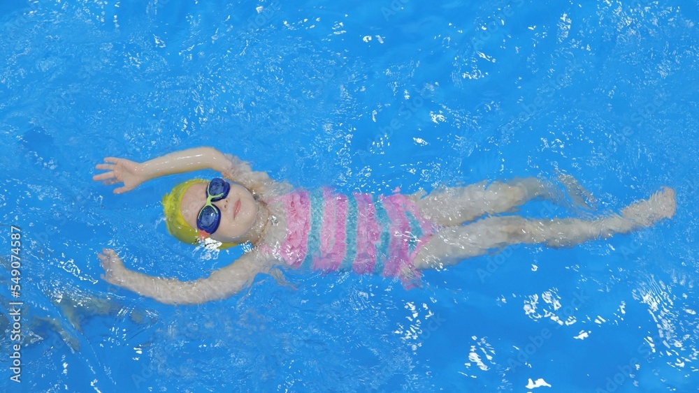 Foto de A little girl swims on her back in the pool. Child, girl learns ...