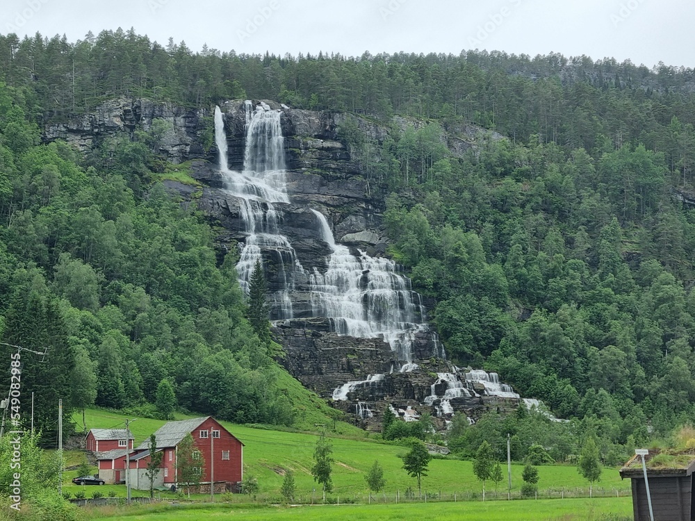 Beautiful view of the Tvindefossen Waterfall in Norway and small houses ...