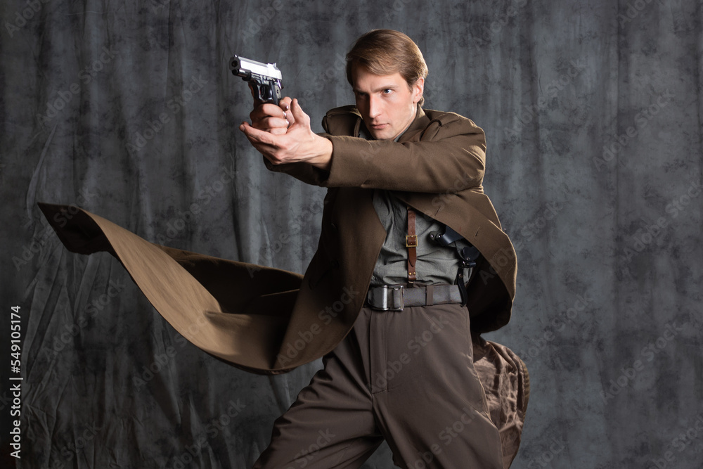 hero in a military style with a gun in his hands, a young man in a long ...