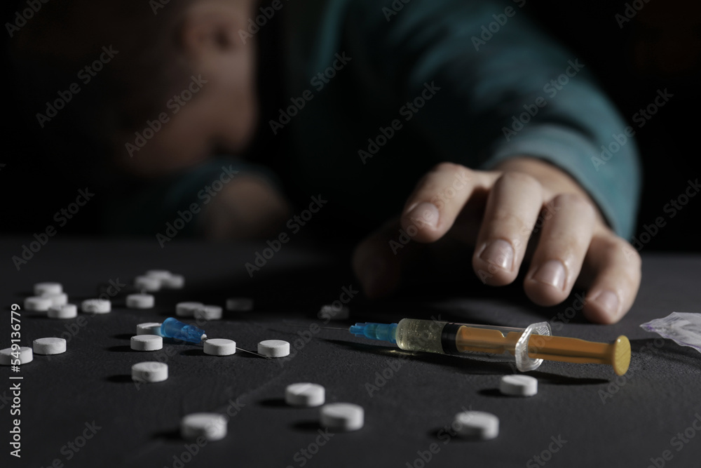 Addicted man reaching to drugs at black table, focus on syringe Stock ...