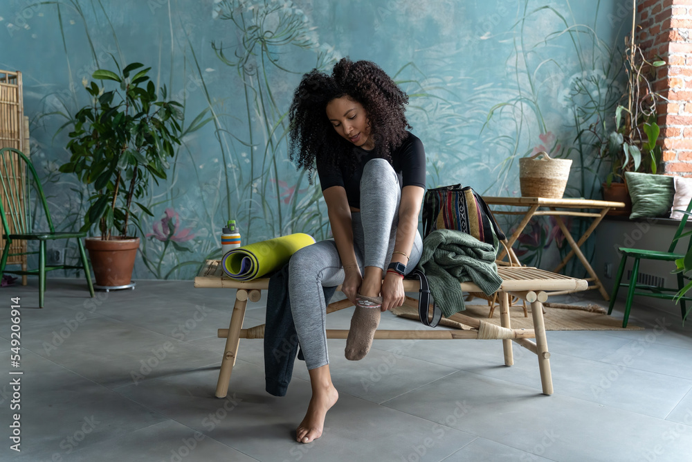 Curly African-American woman putting on clothes after fitness training ...