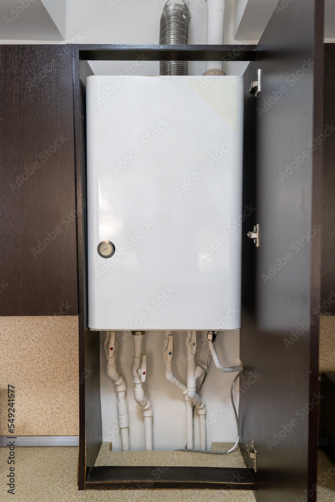Opened kitchen cabinet and LPG gas boiler inside furniture. Gas central ...