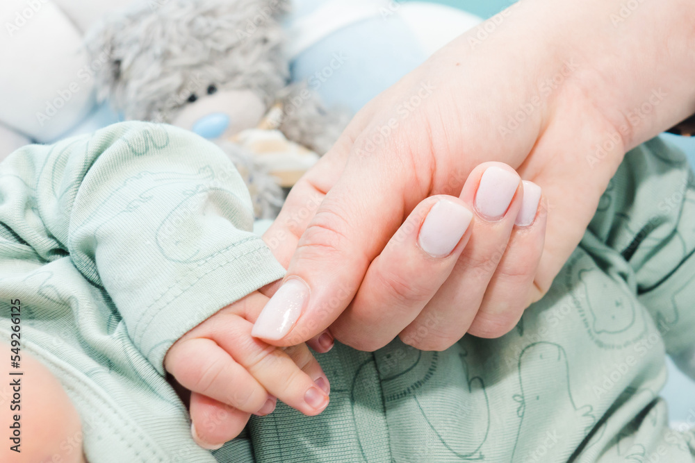Newborn baby touching his mother hand. Mother uses her hand to hold her ...