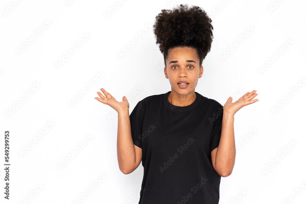 Portrait of bewildered young woman shrugging shoulders against white ...