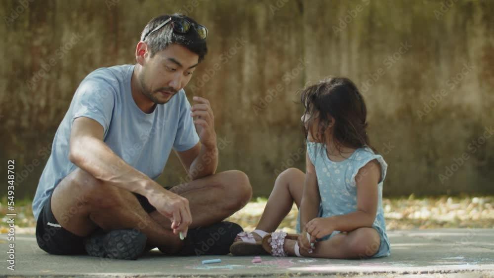 Happy Asian father and little daughter drawing with chalks on asphalt ...