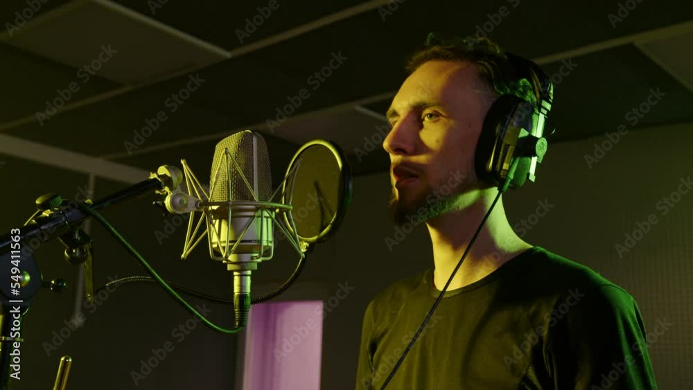 Brutal guy in headphones performs song in recording studio. Young man ...