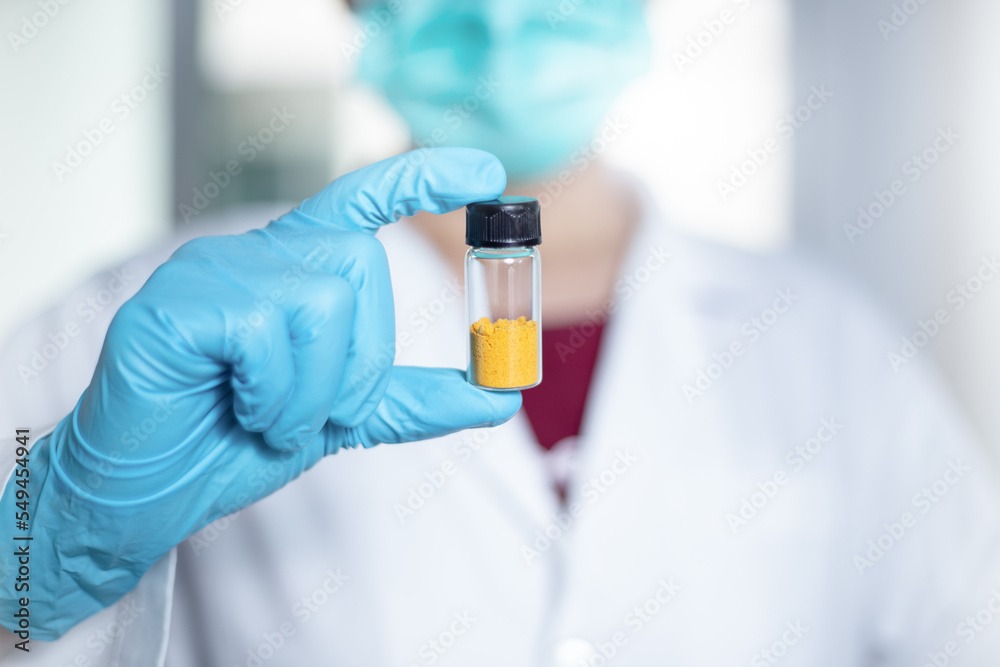 Scientist woman shows orange solid in vial glass of curcumin compound ...
