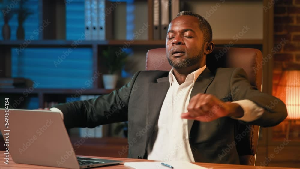 Focused adult businessman working until late in office using laptop ...
