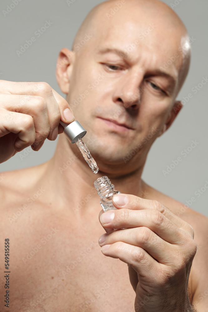 Studio portrait of Caucasian man applying moisturising serum on his ...