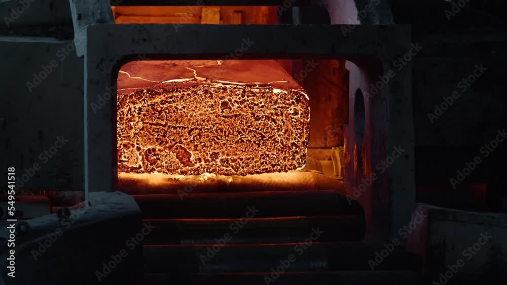 Red hot metal billet moving along a conveyor. A continuous casting and ...