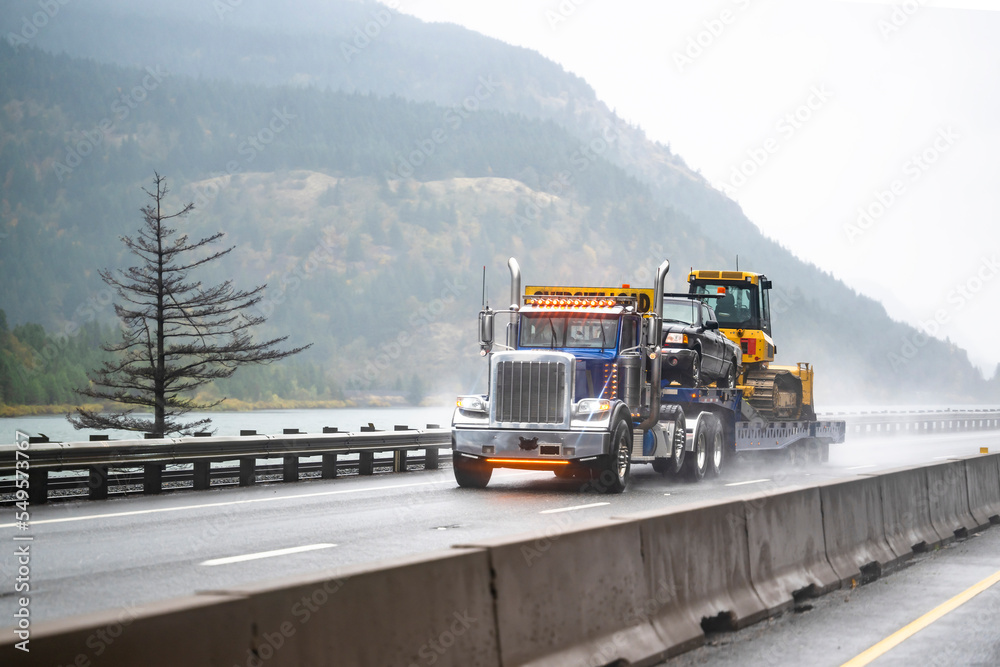 Powerful bright blue big rig classic semi truck tractor with oversize ...