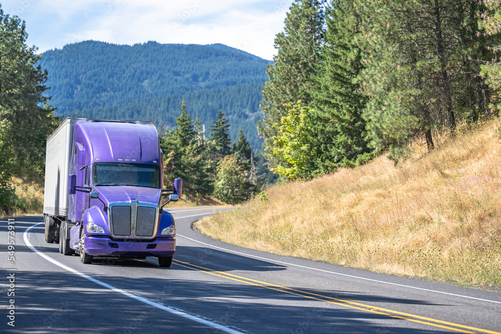 Purple big rig semi truck with reefer semi trailer running with load on ...