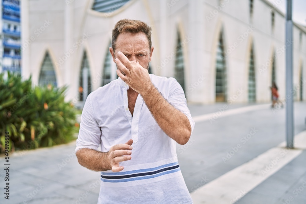 Middle age man outdoor at the city smelling something stinky and ...