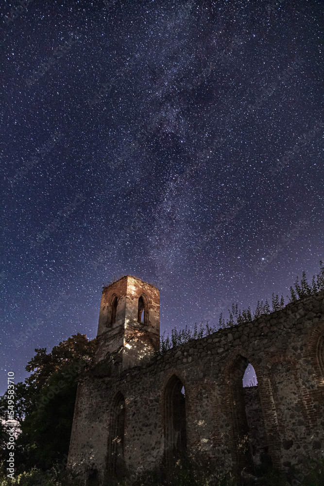 The ruins of Rudau church under the night sky with the Milky Way and ...
