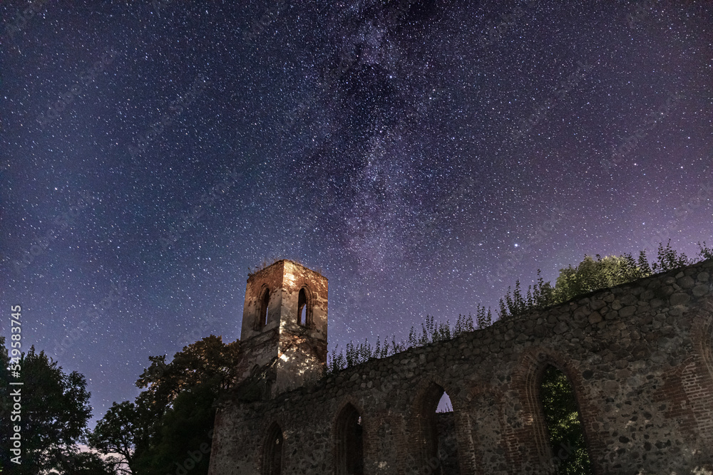 The ruins of Rudau church under the night sky with the Milky Way and ...