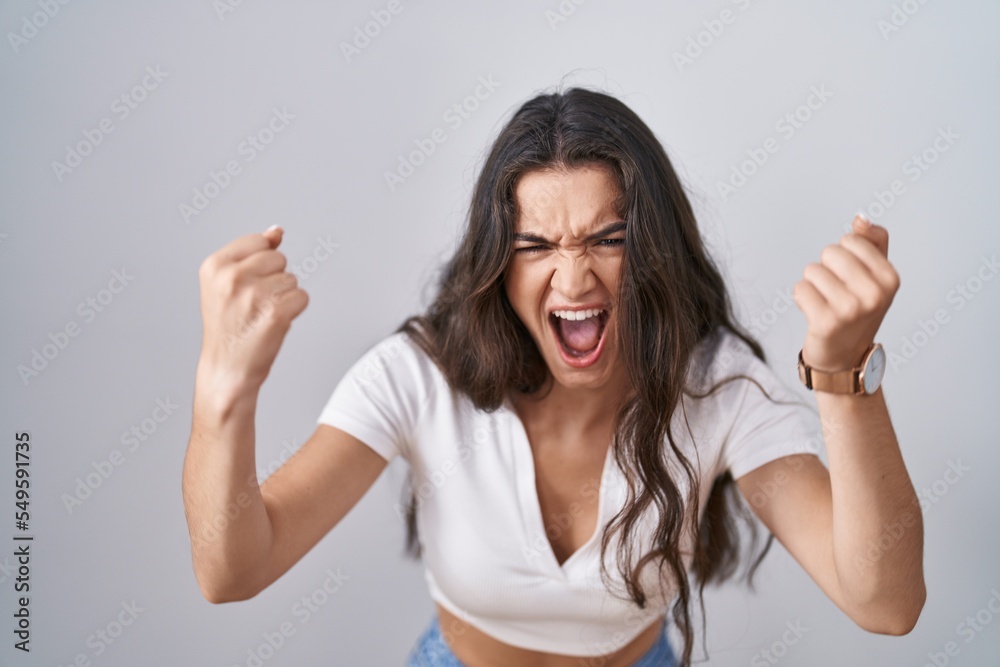 Young teenager girl standing over white background angry and mad ...