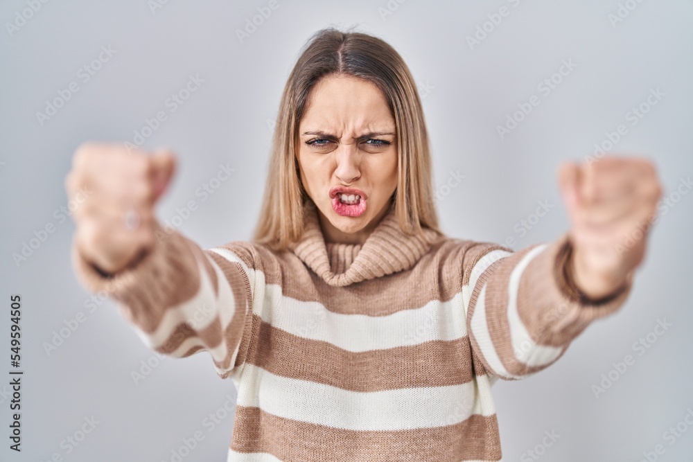 Young blonde woman wearing turtleneck sweater over isolated background ...