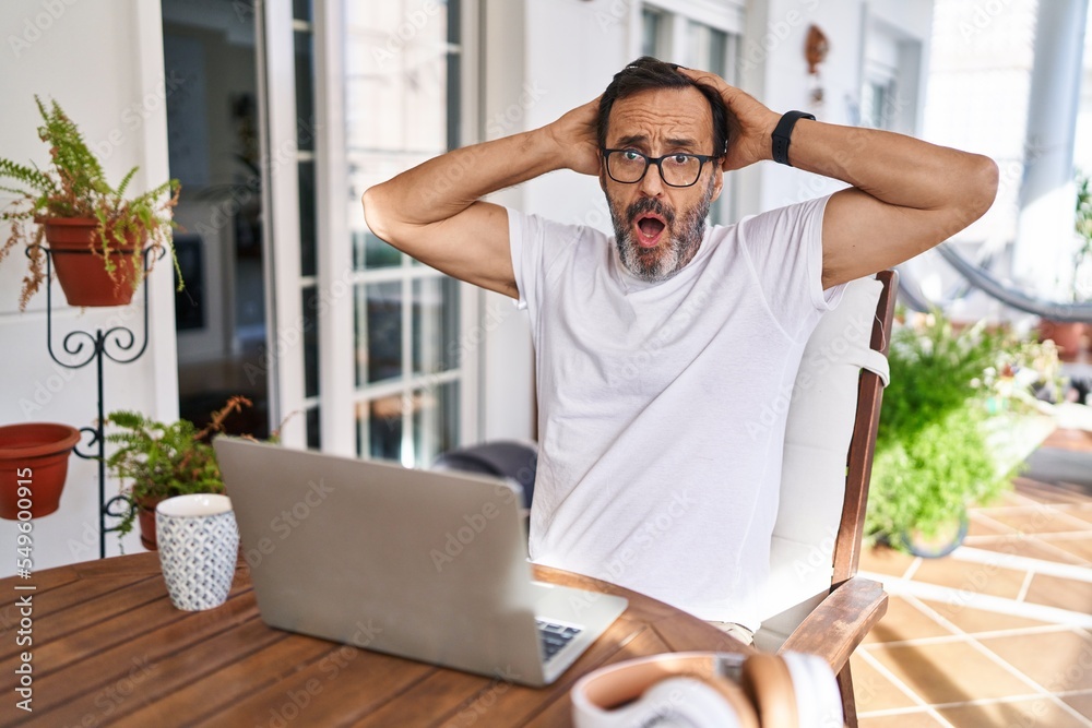 Middle age man using computer laptop at home crazy and scared with ...